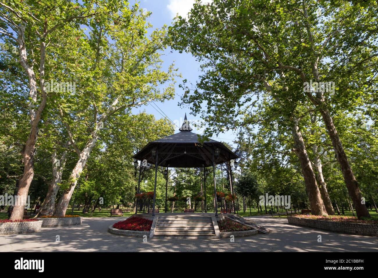 Bandstand in a city park in summer, surrounded by gardens and tall ...