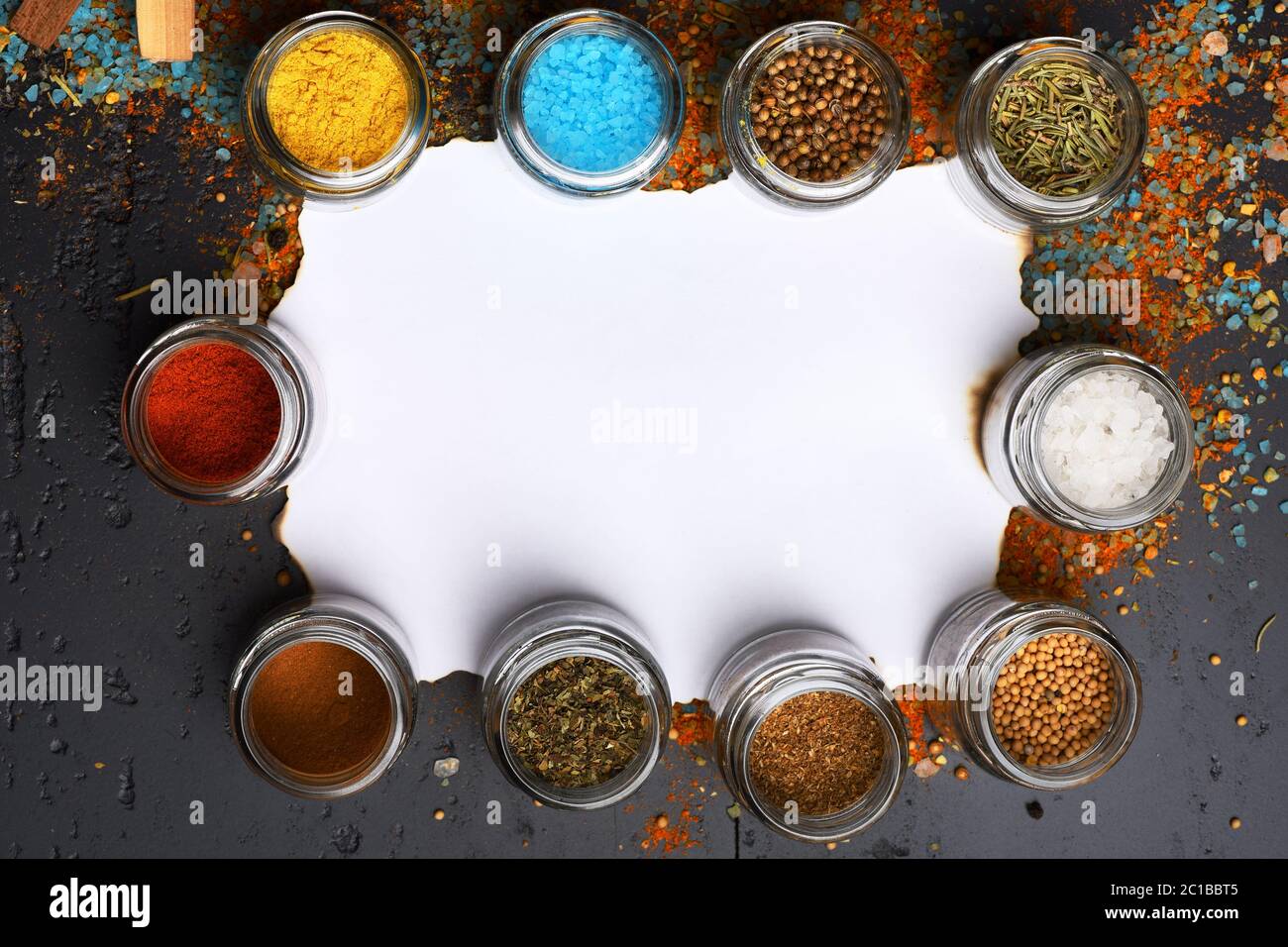Glass jars with paprika, mustard, oregano and other spices near granulated sea salt. Food art ...