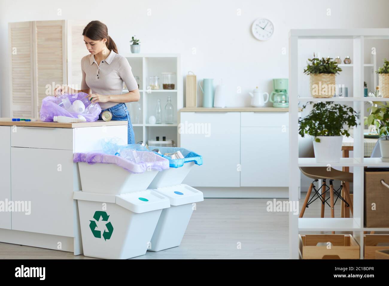 Young woman examining the bag with garbage she sorting trash into the ...