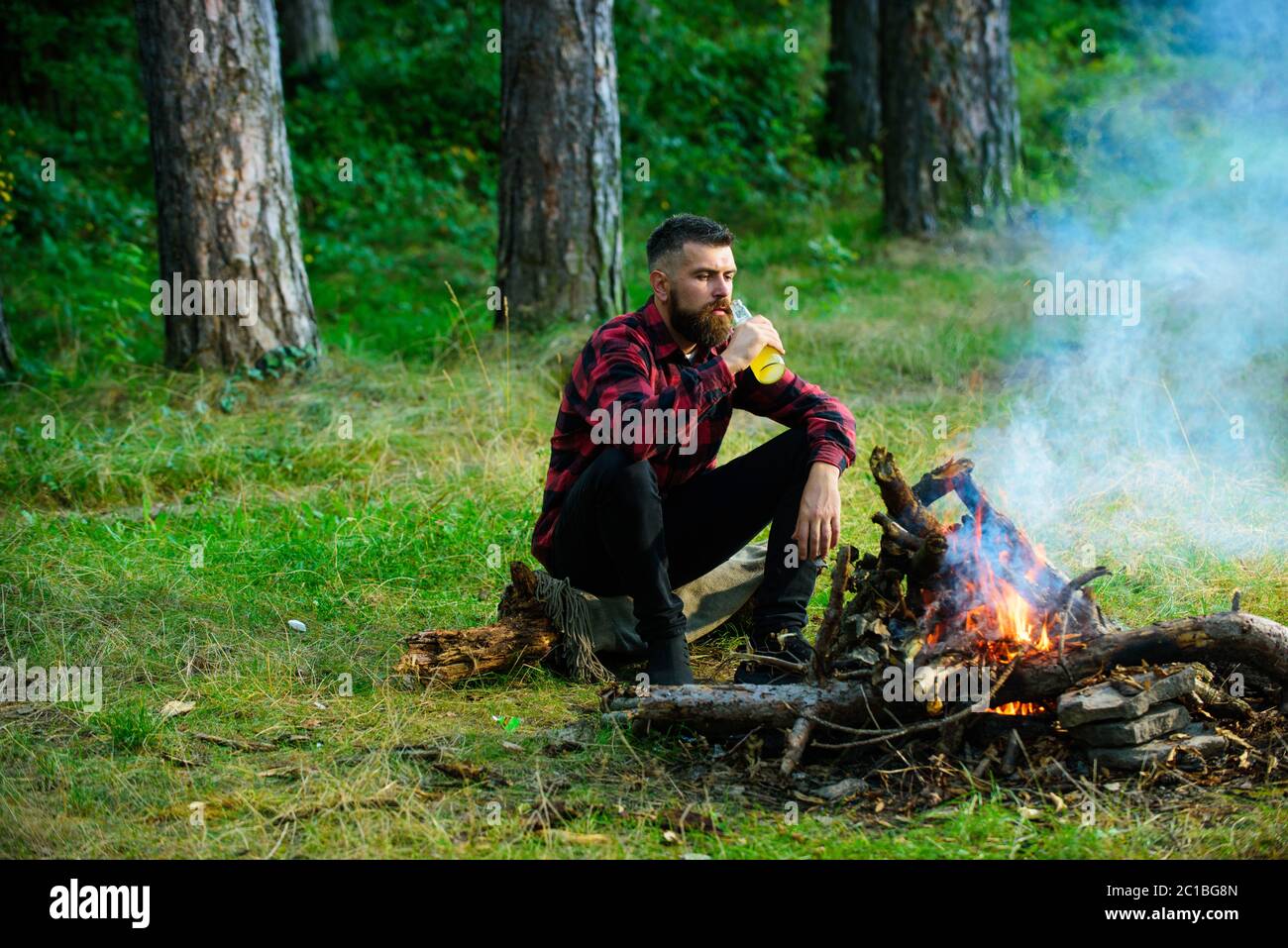 Handsome macho with beer sitting near bonfire, enjoying vacation ...
