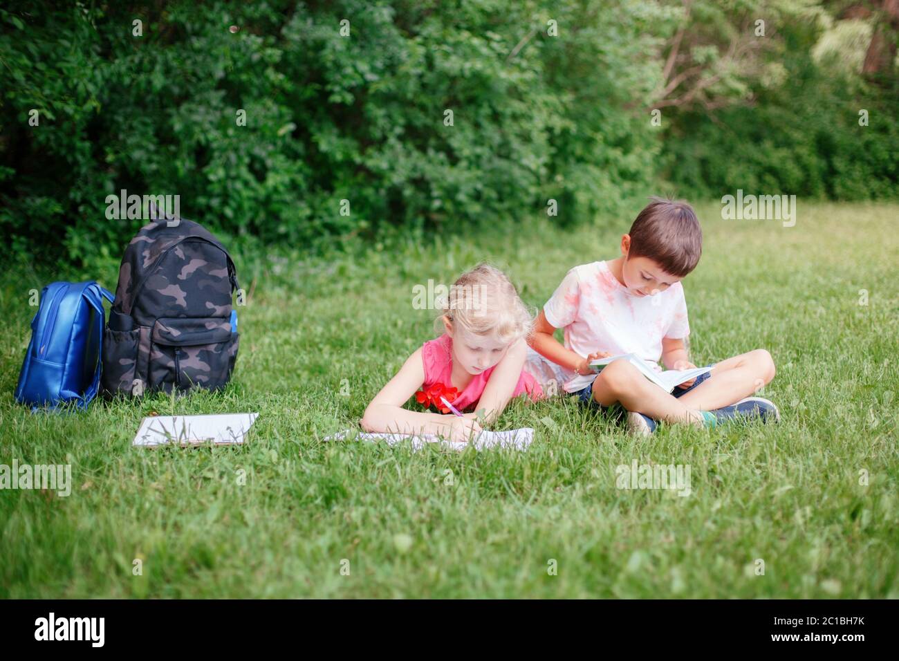 Young Caucasian school girl and boy friends doing school homework in ...