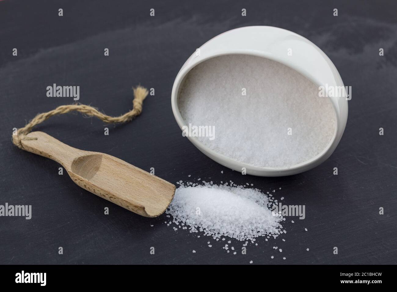 Salt heap on black background with chef's salt bowl and wooden scoop ...