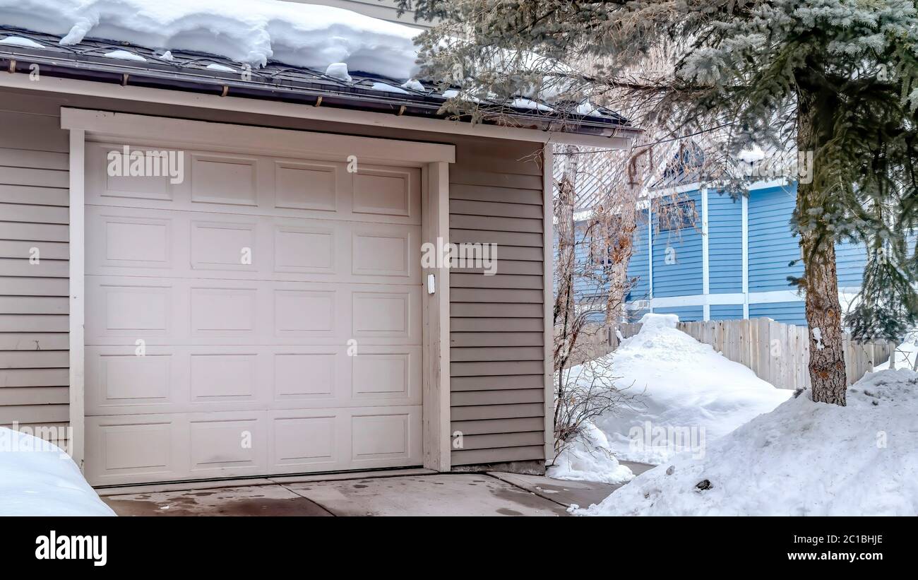 Panorama White garage door entrance of home with snow covered roof and ...