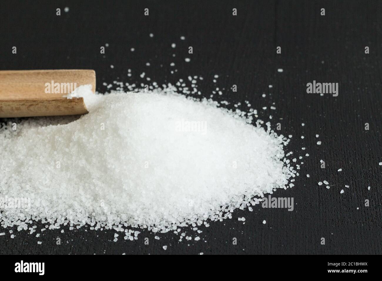 Salt on black background with wooden scoop close up Stock Photo - Alamy