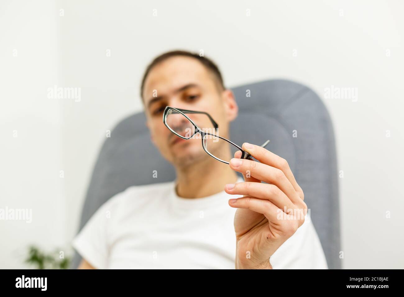 Young man puts his glasses on Stock Photo - Alamy