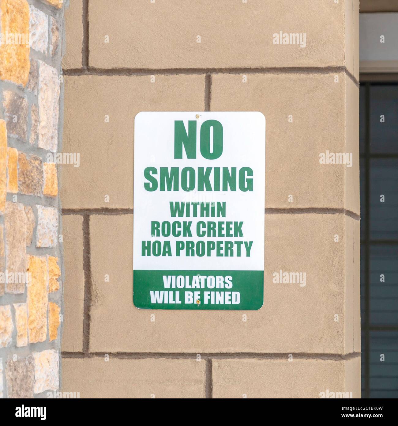 Square No Smoking sign on the exterior stone wall of apartment in Rock ...