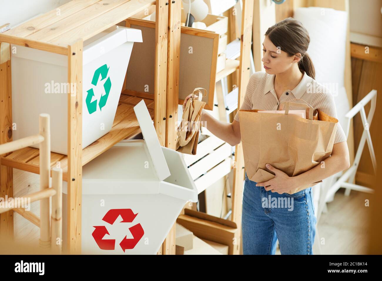 Young woman sorting paper bags into the plastic containers while ...