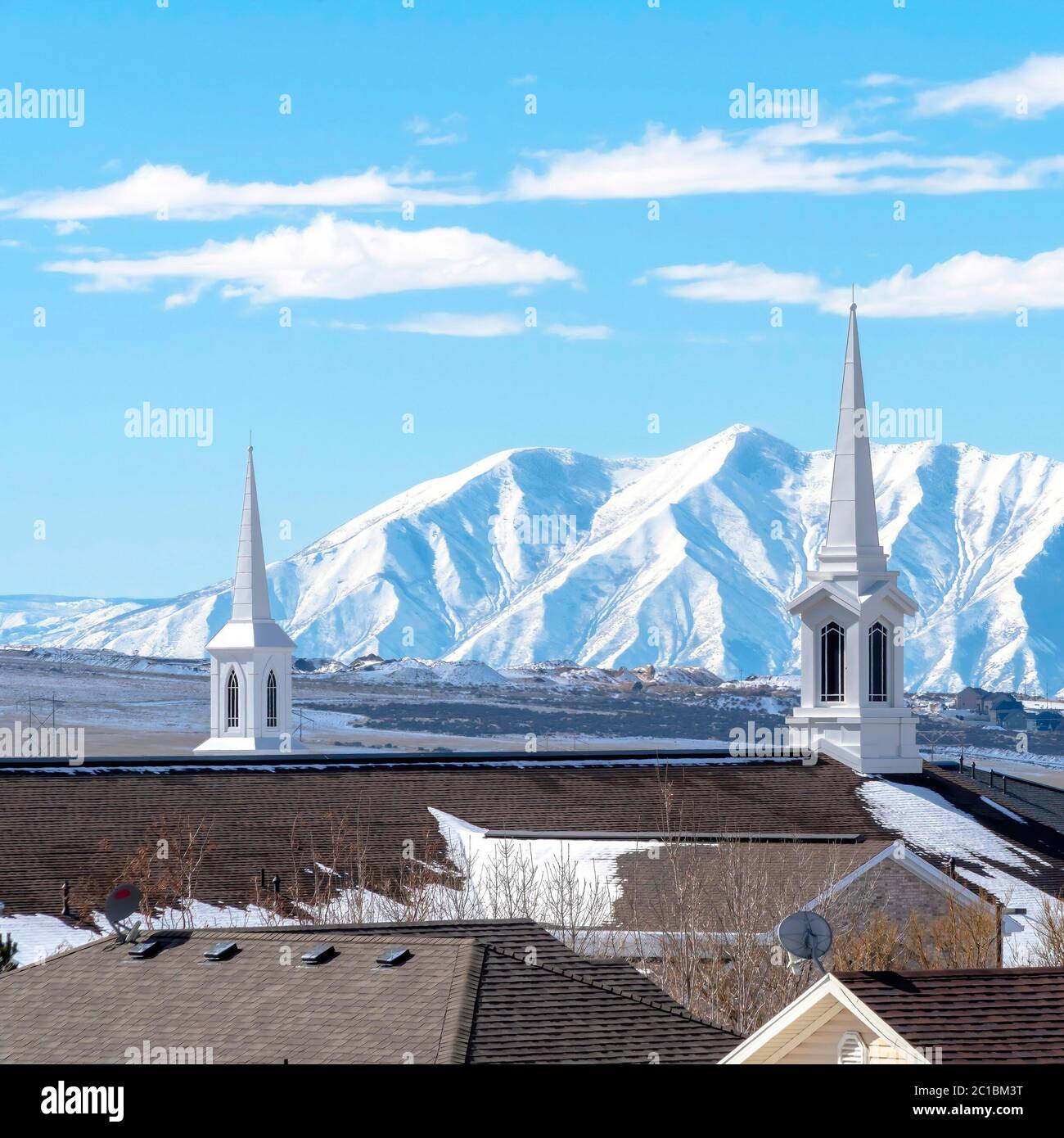 Square Modern spires of church with steep snowy mountain and sunny blue ...