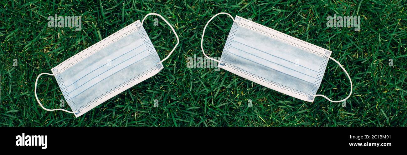 Two fresh new sanitary masks lying on grass. Disposable recyclable face ...