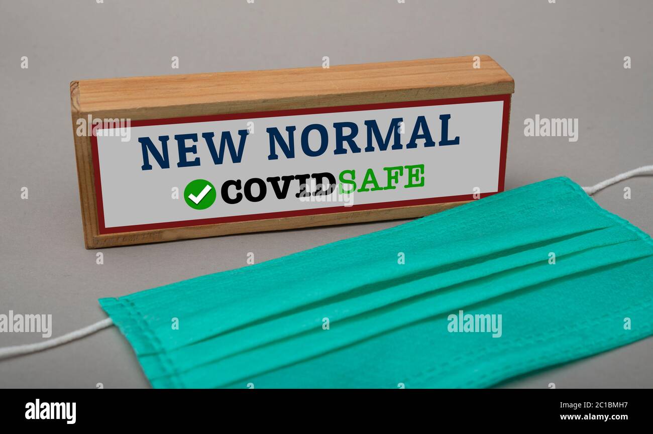Text of now normal covid safe on table sign with surgical mask photo ...