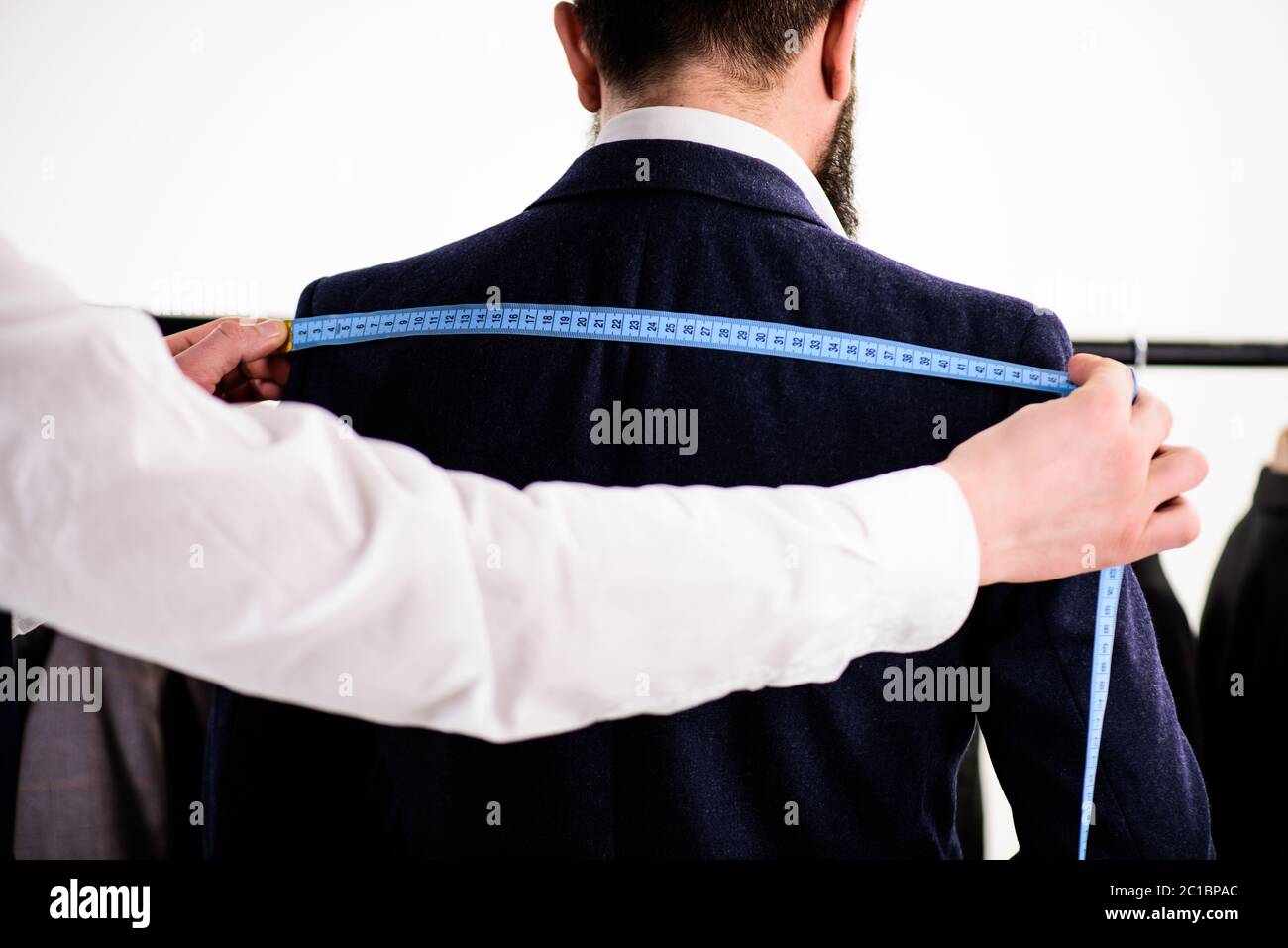 Tailors hands measure back for sewing suit, white background. Taking ...