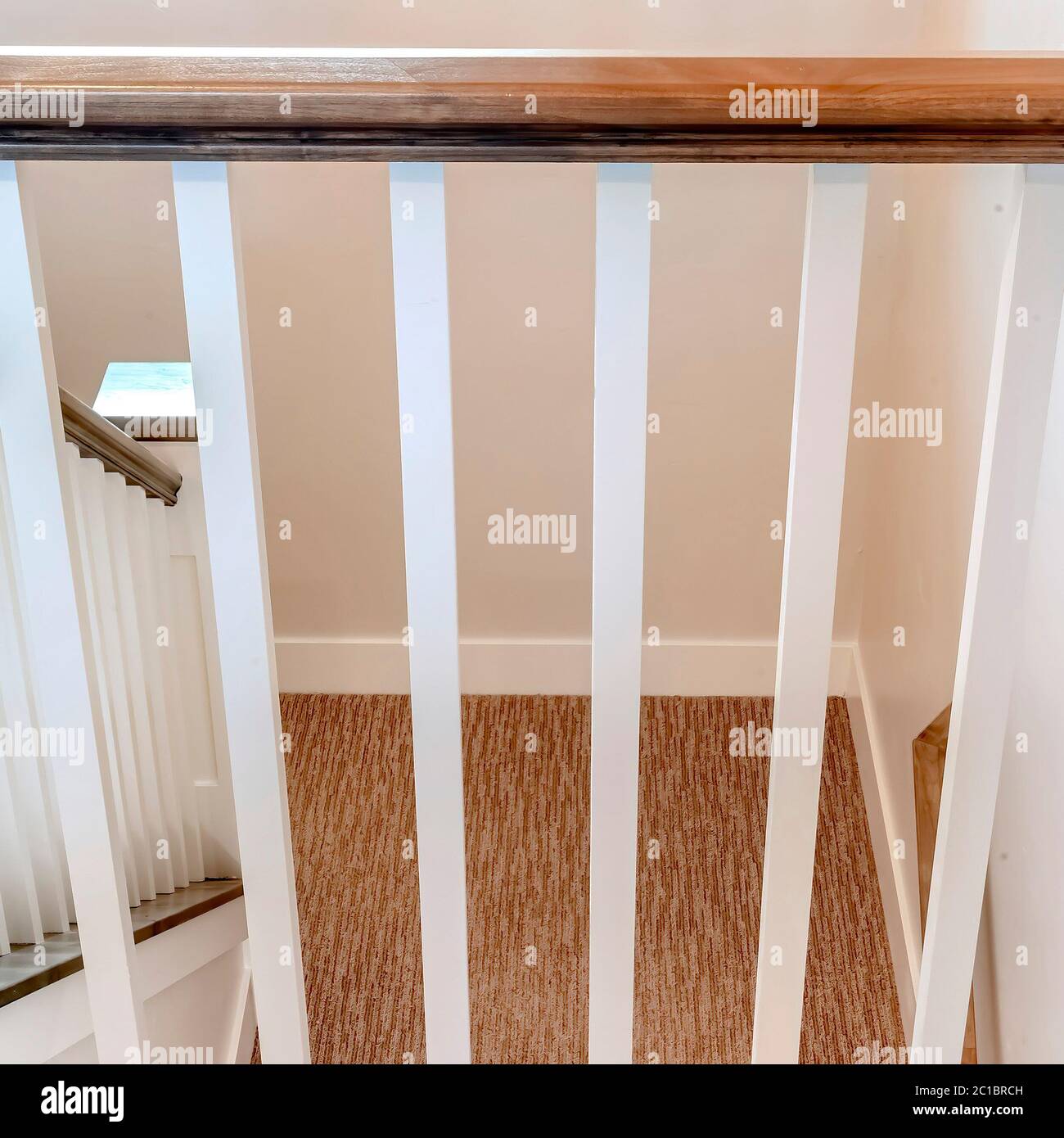 Square frame U shaped stairway of home with brwon handrail supported by ...