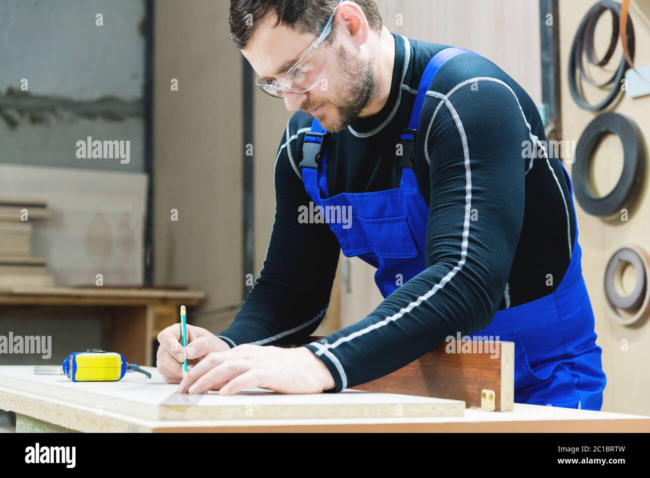 A bearded tired handsome carpenter on a table with a pencil draws a ...