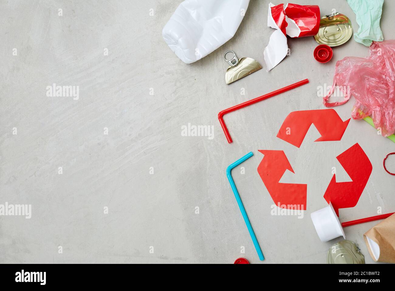 Close-up of red recycling symbol with waste isolated on grey background ...