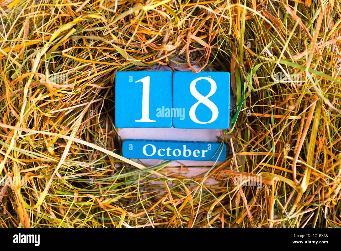 October 18. Blue cube calendar with month and date on dry straw ...