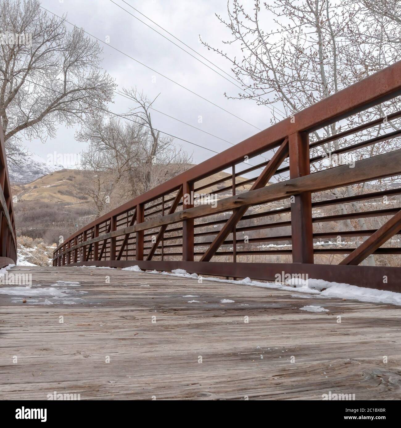 Square Bridge with metal railing and melting snow on the wooden landing ...