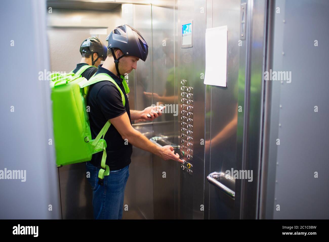 Food delivery concept. The food delivery man goes up in the elevator to ...