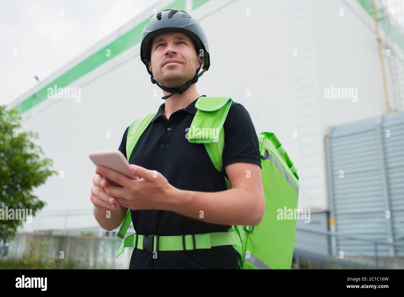 Food delivery concept. The food delivery man uses a smartphone to reach ...