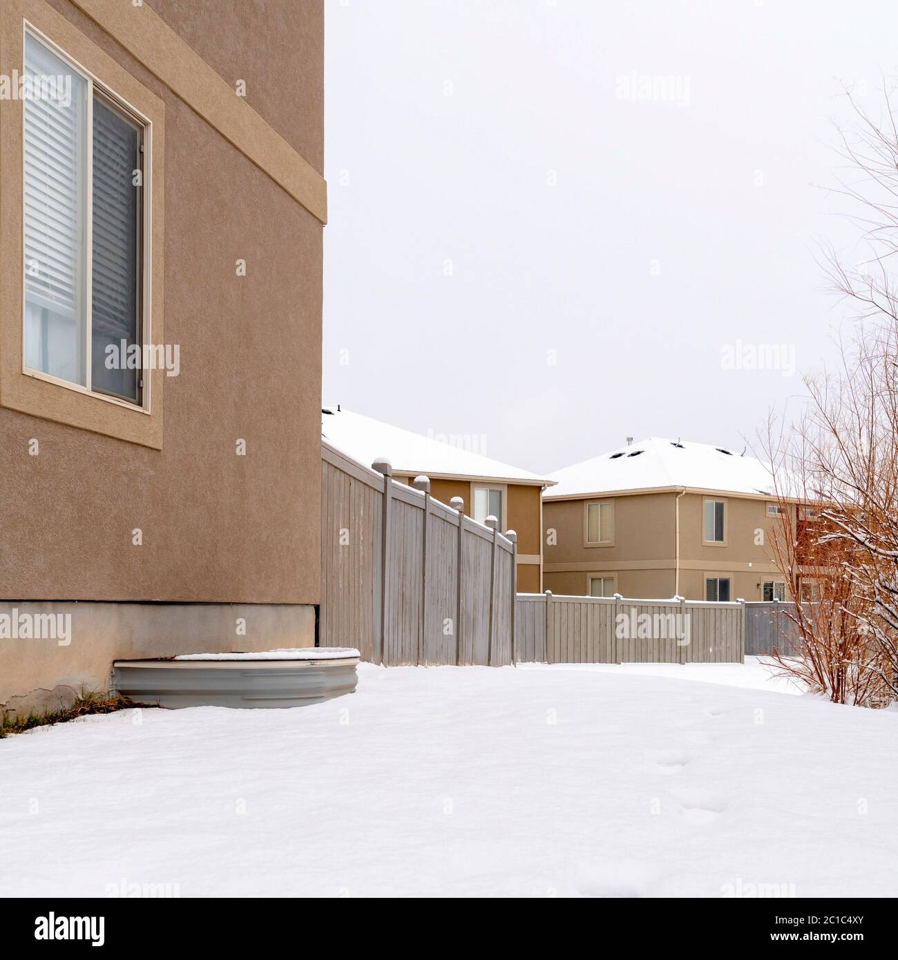 Square Ground blanketed with snow in front of houses and woodne fence ...