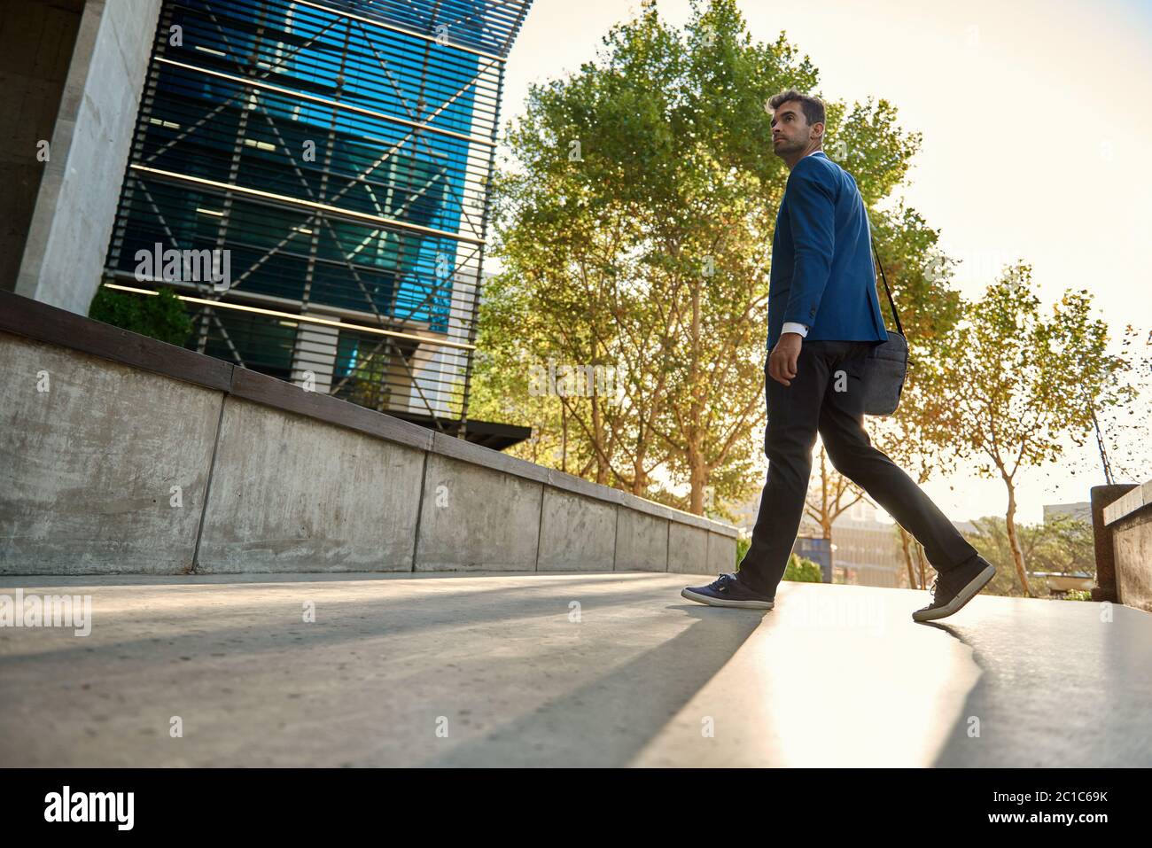 Stylish young businessman walking through the city to work Stock Photo ...