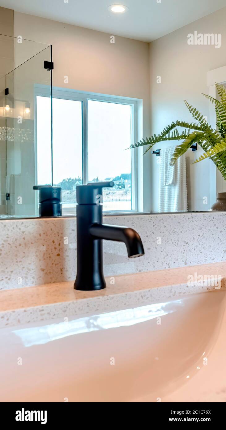 Vertical Sink and faucet against mirror that reflects shower stall and ...