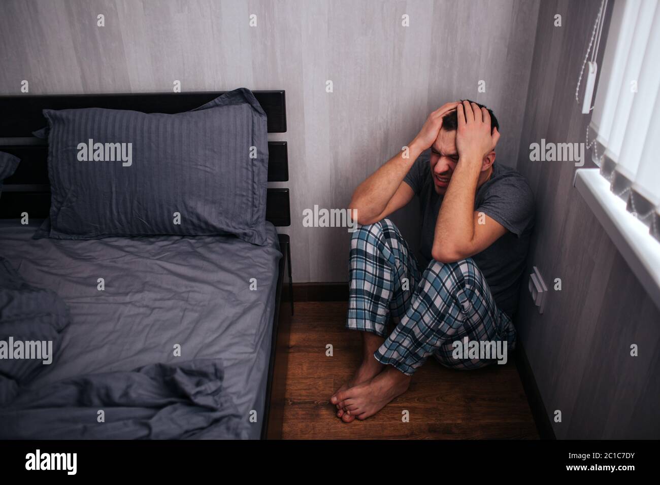 Depression, panic attack concept. A man is sitting in a corner near the ...