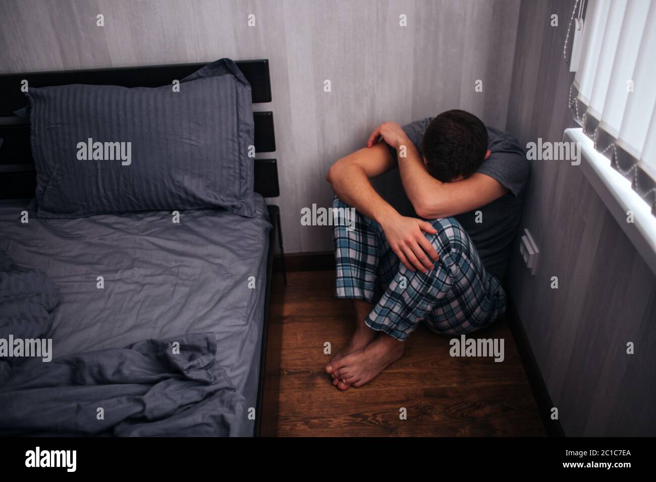 Depression, panic attack concept. A man is sitting in a corner near the ...