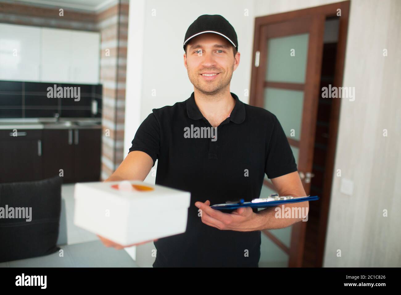 The delivery man or courier looks at the camera and gives the goods or ...