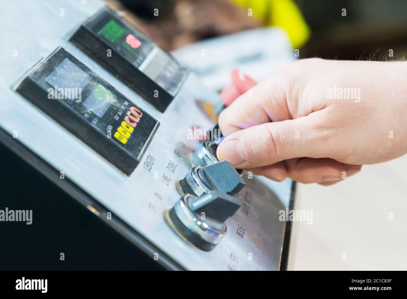 A close-up of a man's hand holds a rotary switch on the equipment ...
