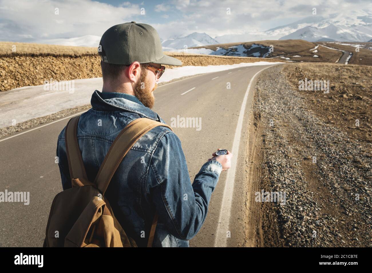 Hipster man using a compass on a snowy mountain Stock Photo - Alamy