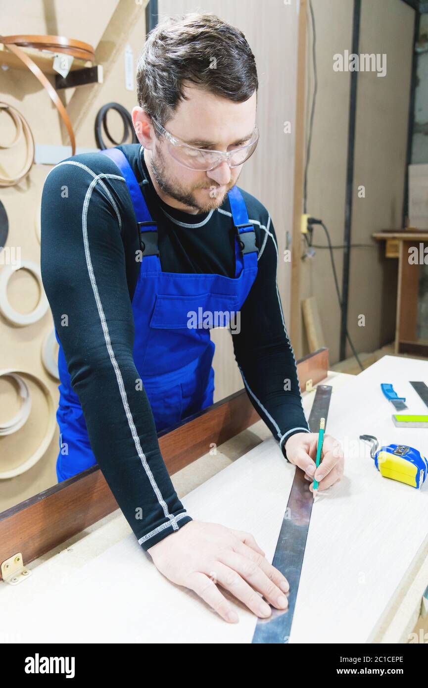 A bearded tired handsome carpenter on a table with a pencil draws a ...