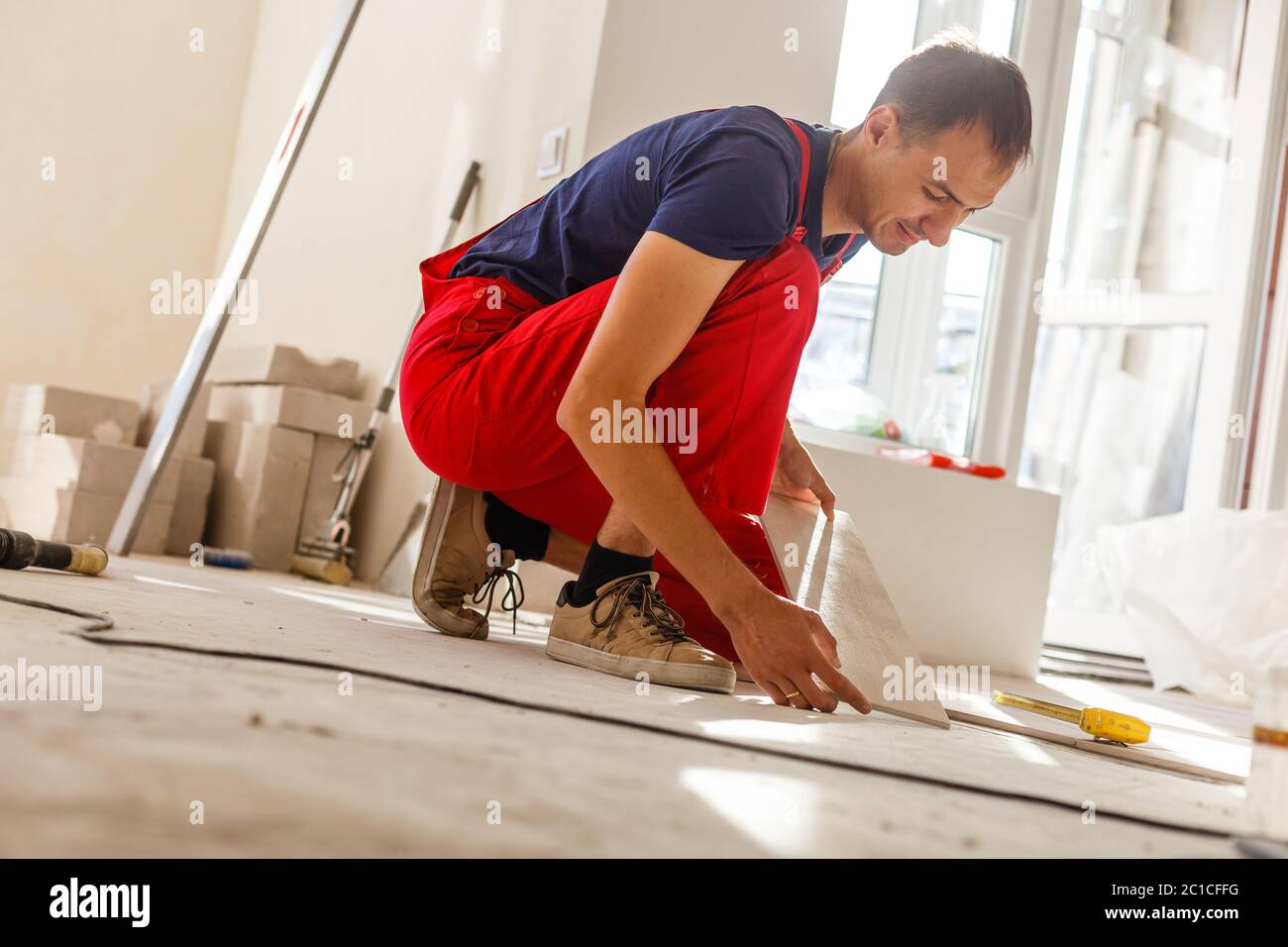 Master is wearing work clothes, is checking horizon of installing tiles ...