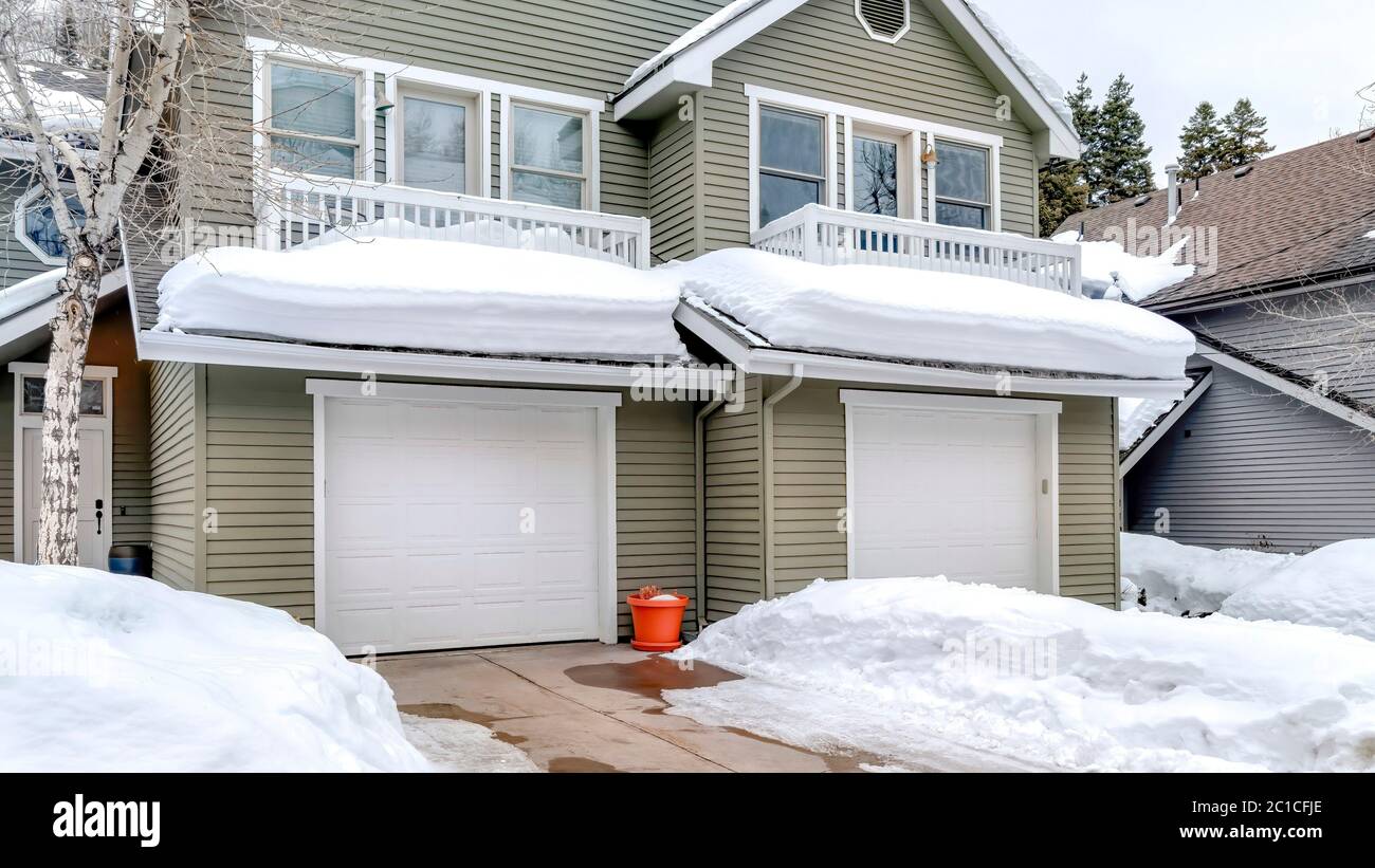 Panorama Facade of home with snowy driveways in front of two car garage ...