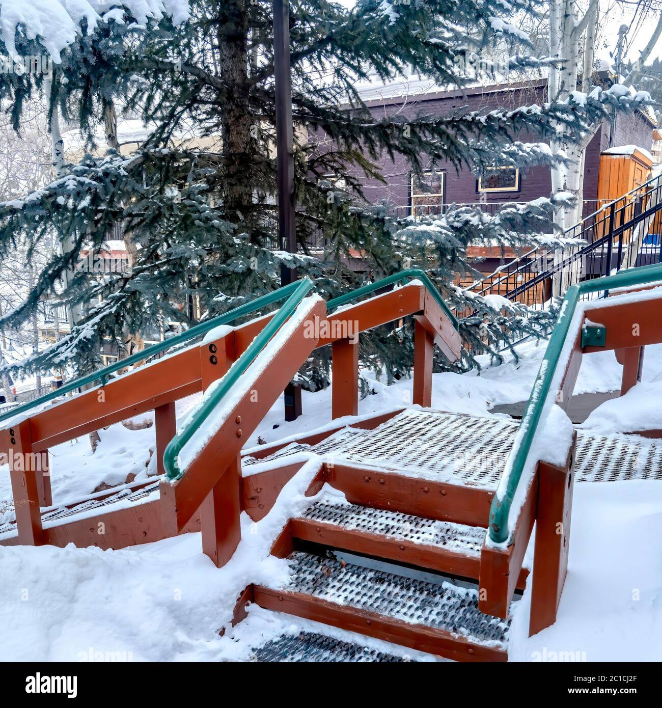 Square Stairs with green handrails and grate metal treads built on hill ...