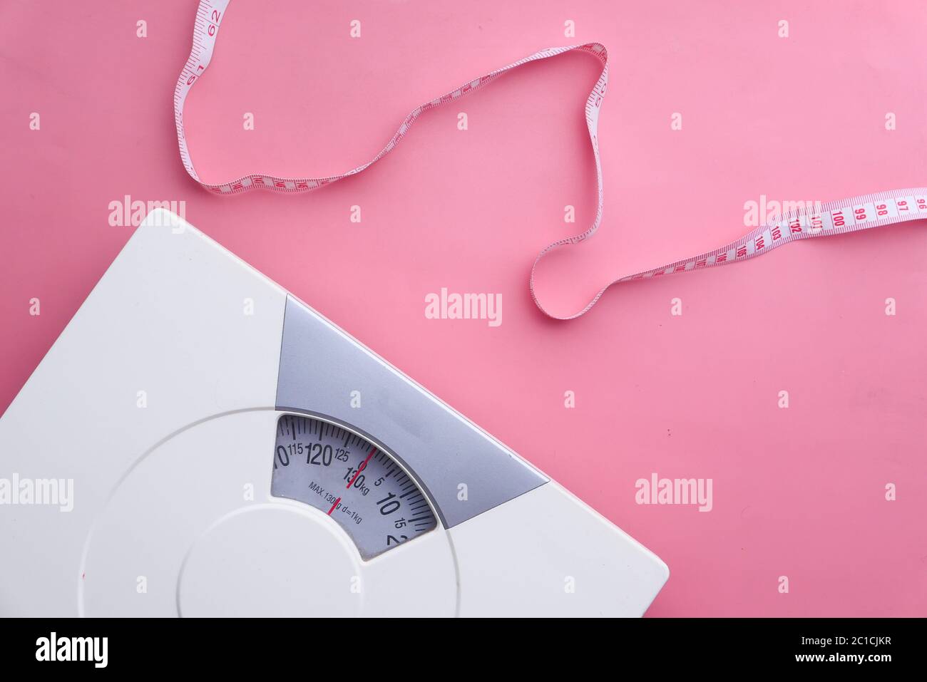 a tape measure and Bathroom scale on pink background Stock Photo - Alamy