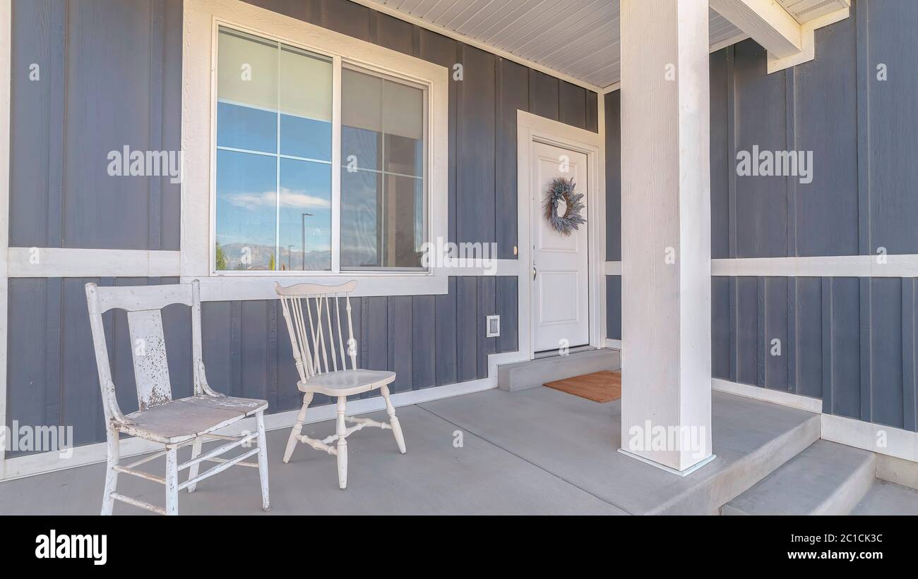 Panorama White porch chairs against window and front door of home with ...