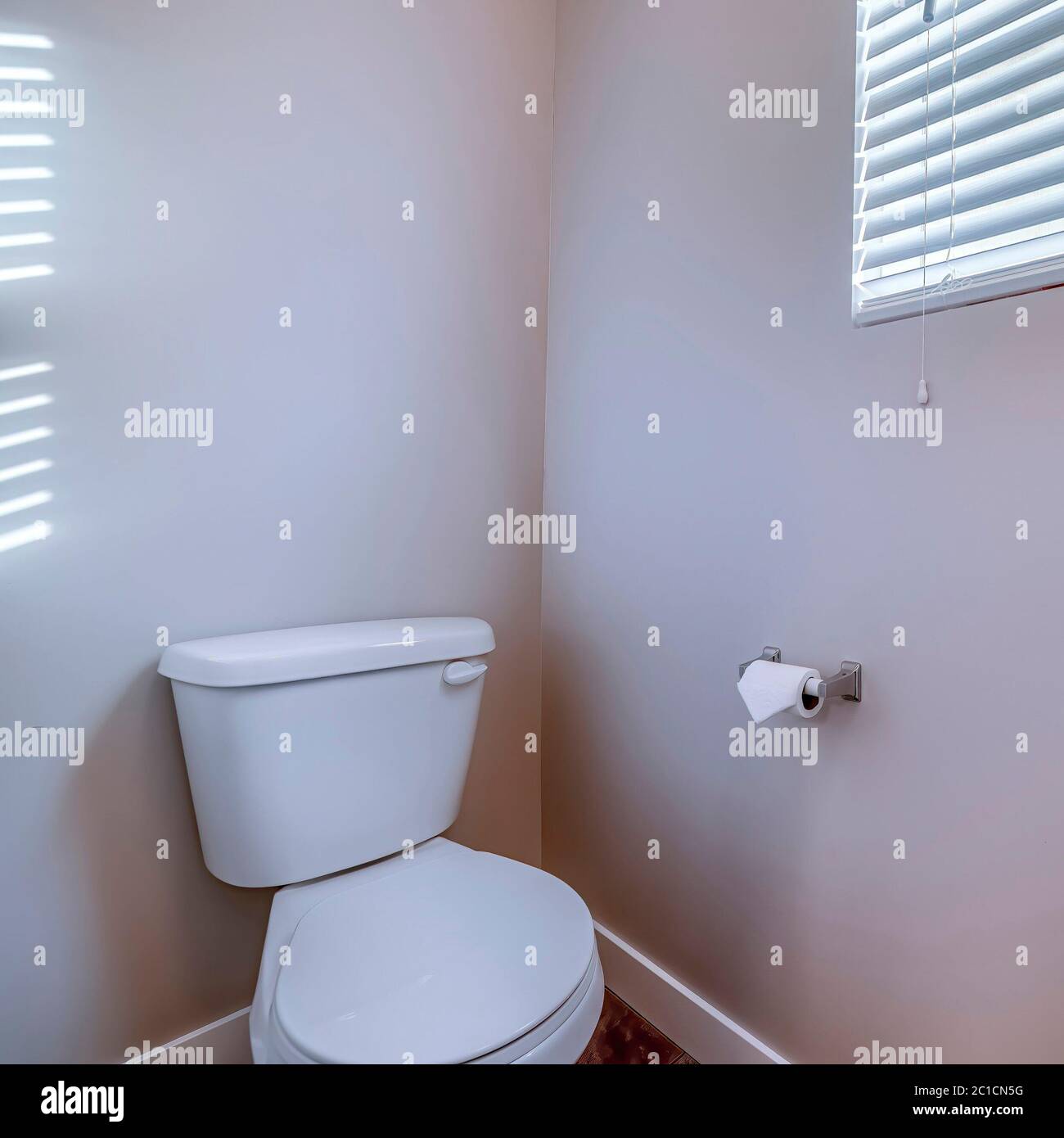 Square frame Toilet at the corner of a bathroom against gray wall with ...