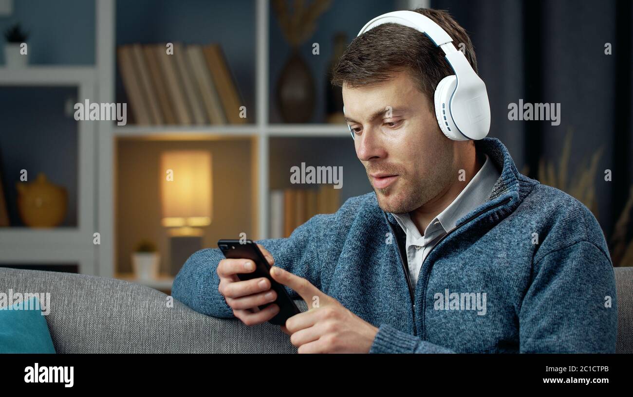 Man using gadgets sitting sofa Stock Photo - Alamy