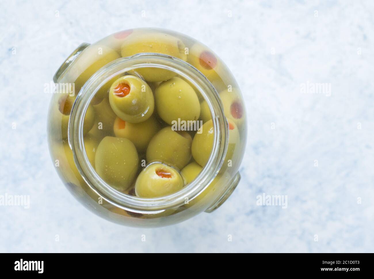 Jar of stuffed green olives in brine close up top view photo with copy ...