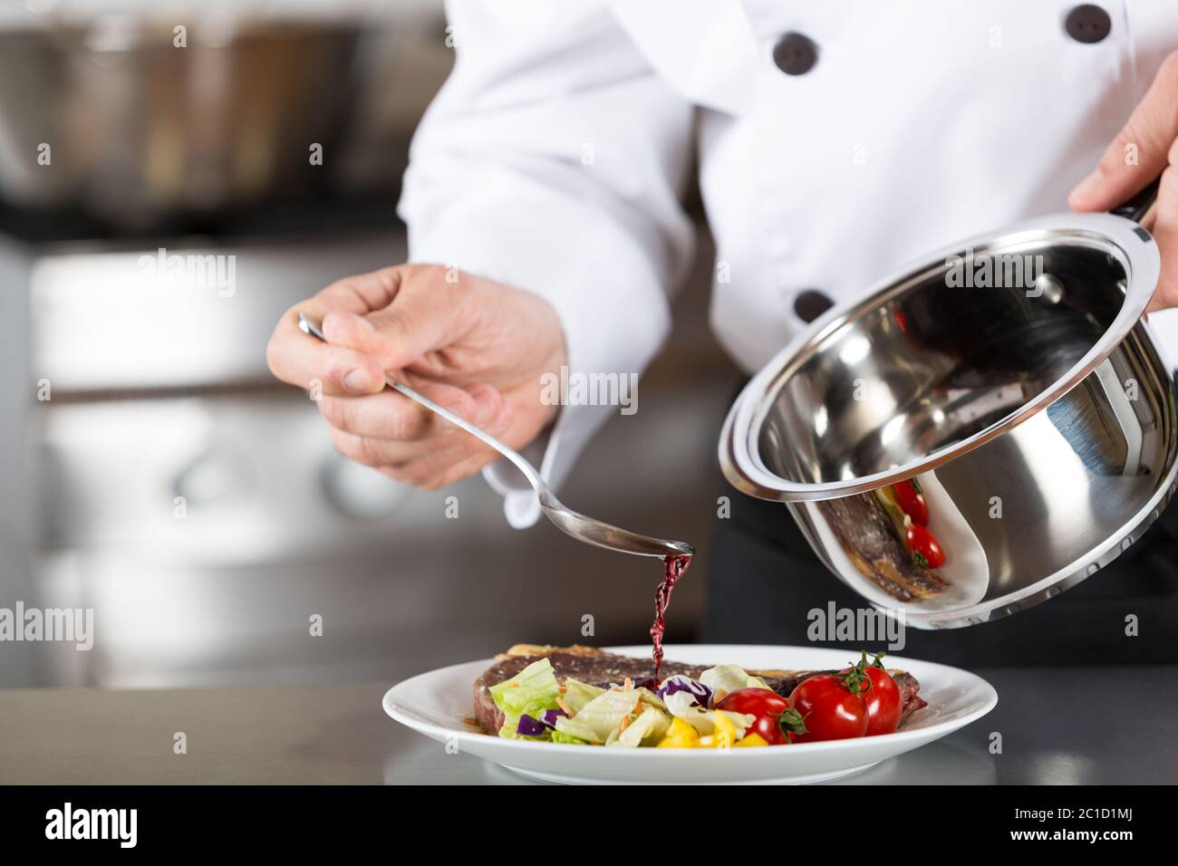 Chef finishing her plate and almost ready to serve at the table Stock ...