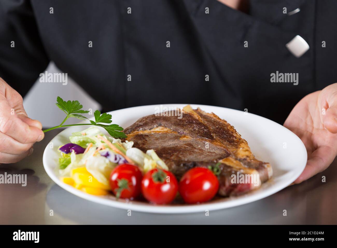 Chef finishing her plate and almost ready to serve at the table Stock ...