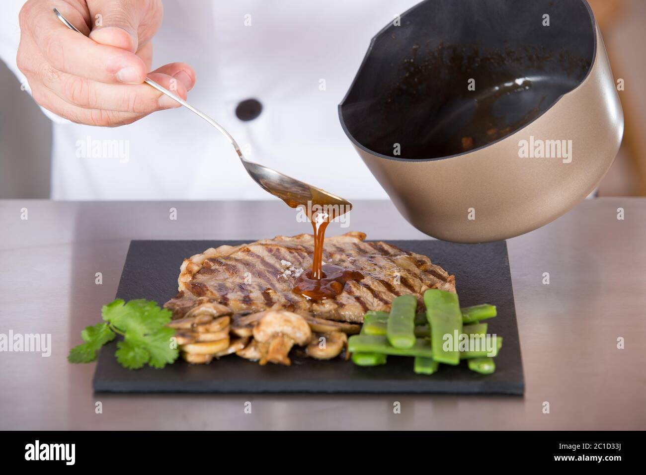 Chef finishing her plate and almost ready to serve at the table Stock ...