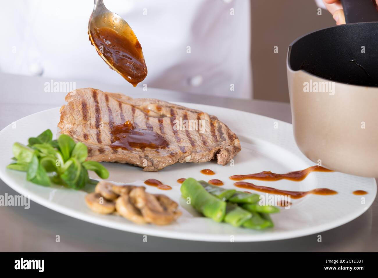 Chef finishing her plate and almost ready to serve at the table Stock ...