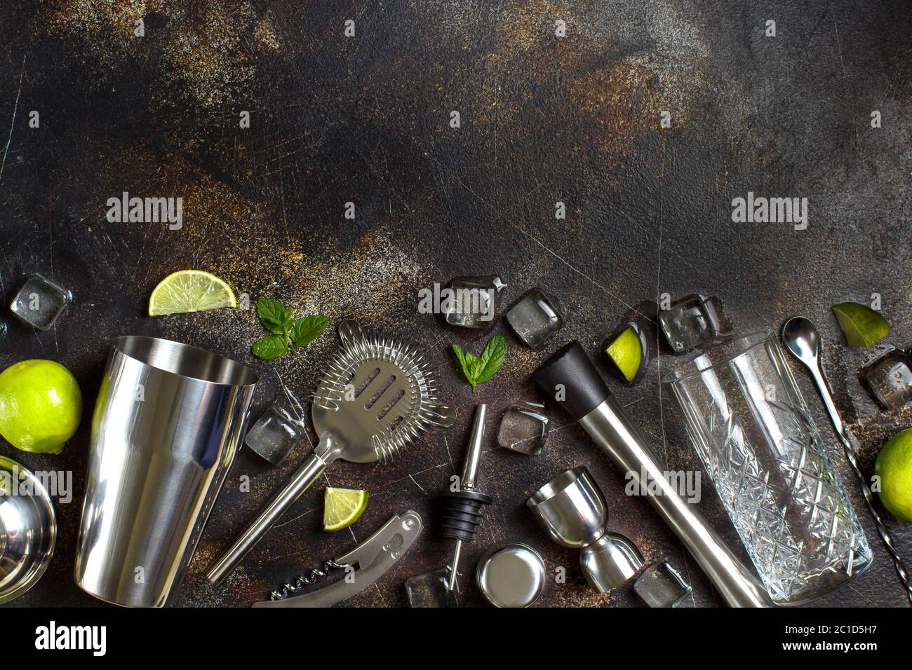 Bartender tools, ice, mint and lime for cocktail making on a dark table ...