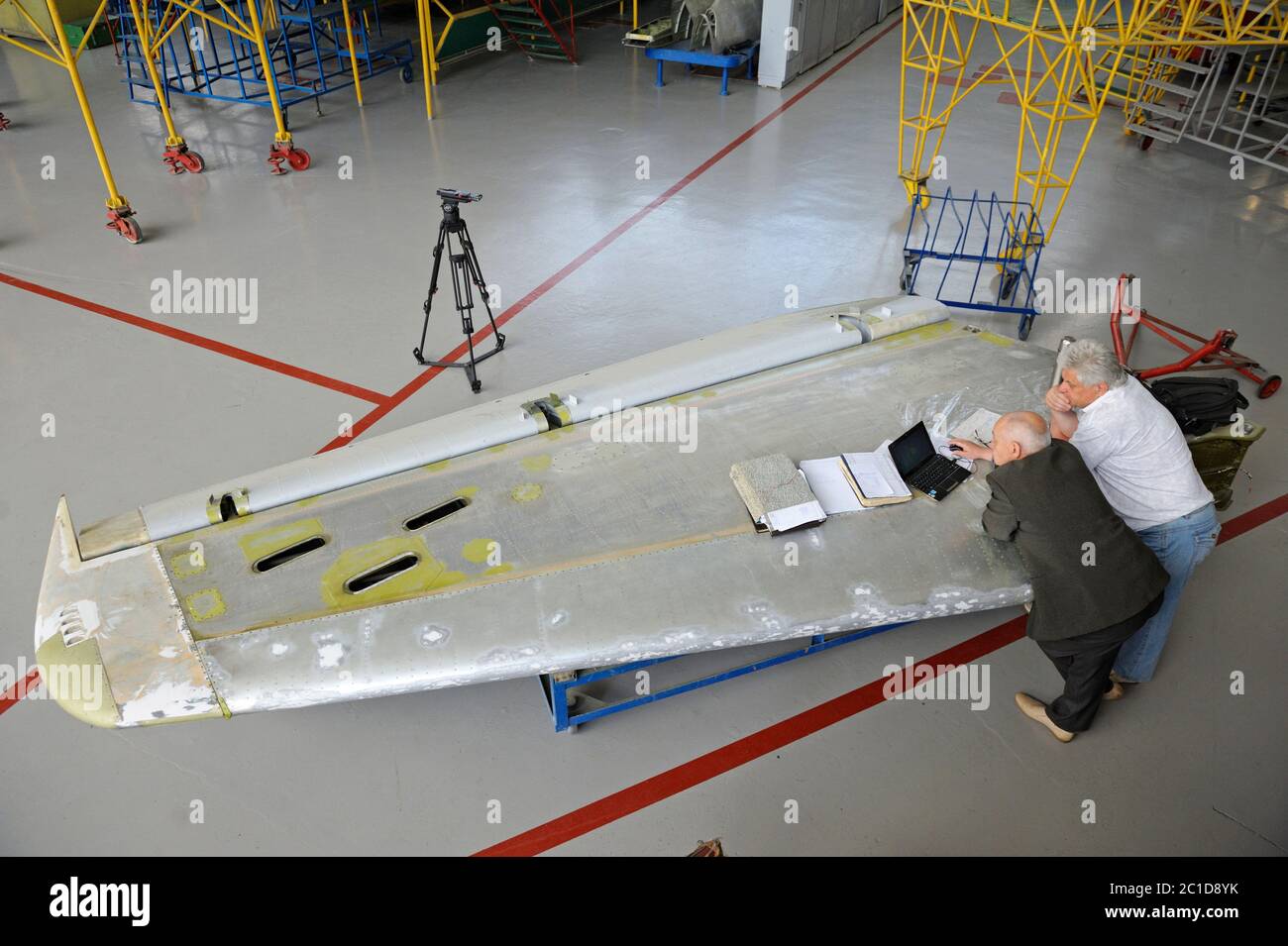 At the maintenance hall. Engineers standing at the wing of plane used ...