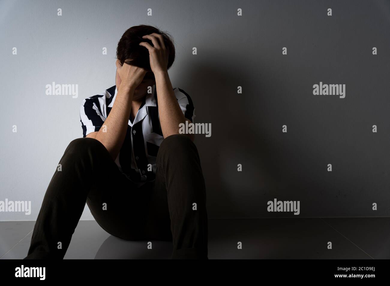 sad man hug her knee and cry sitting alone in a dark room. Depression ...