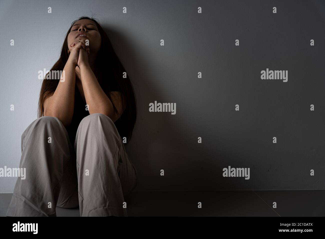 sad woman hug her knee and cry sitting alone in a dark room. Depression ...