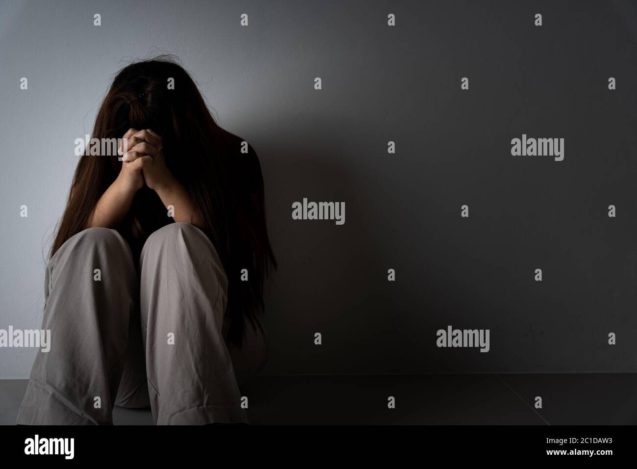 sad woman hug her knee and cry sitting alone in a dark room. Depression ...