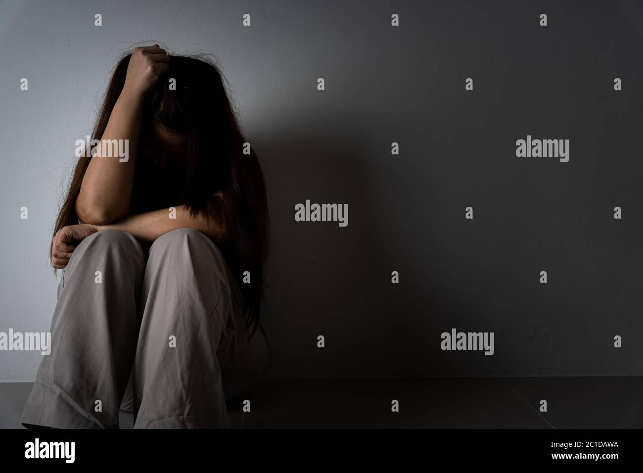 sad woman hug her knee and cry sitting alone in a dark room. Depression ...