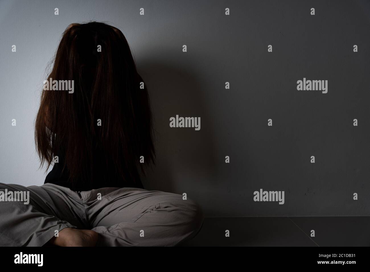 sad woman hug her knee and cry sitting alone in a dark room. Depression ...